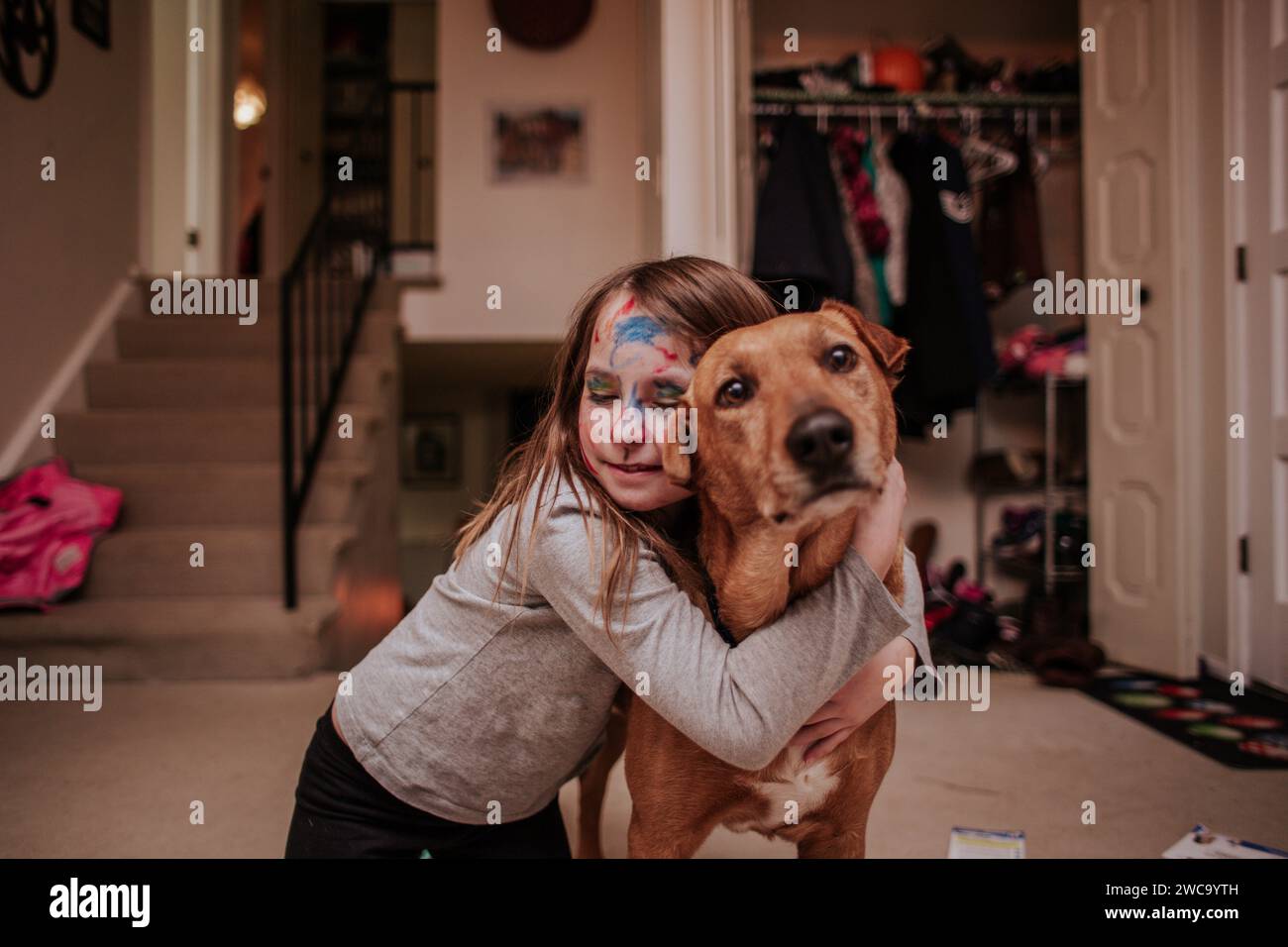 Young girl with paint on face hugging dog Stock Photo - Alamy
