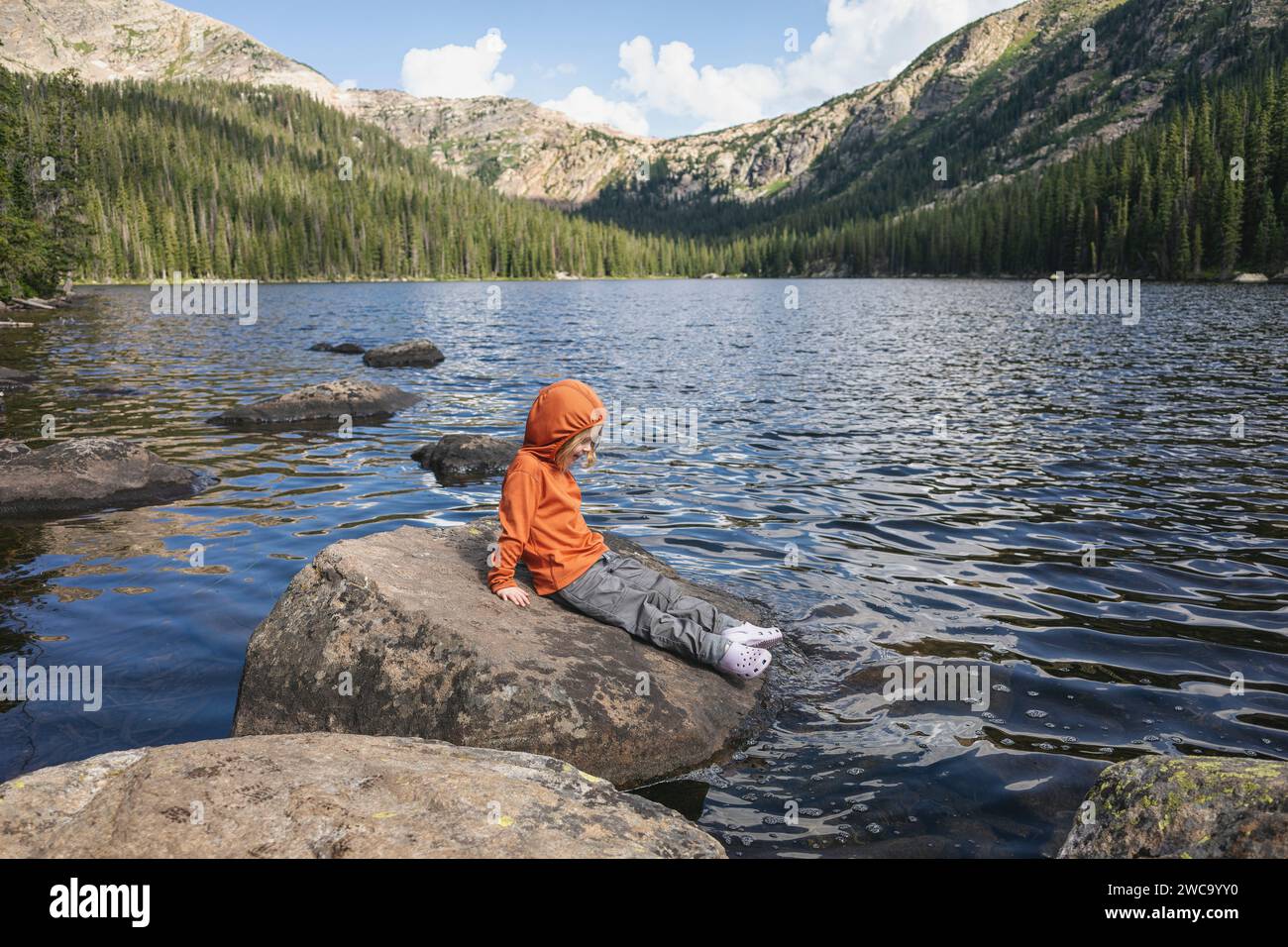 Child exploring nature sitting on a boulder by Timberline Lake Stock ...