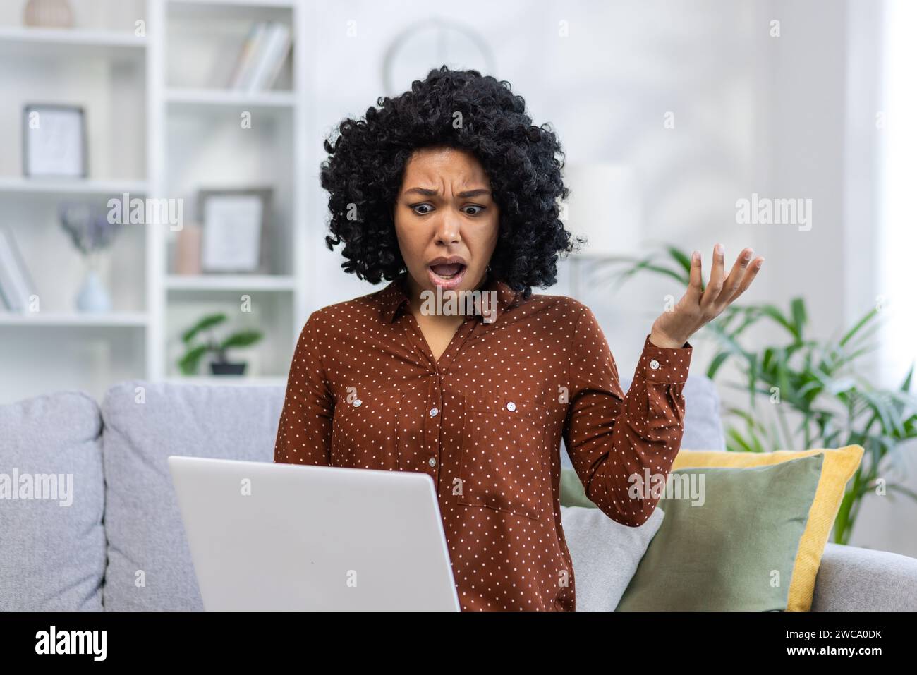 Angry young African American woman sitting on the couch at home and ...