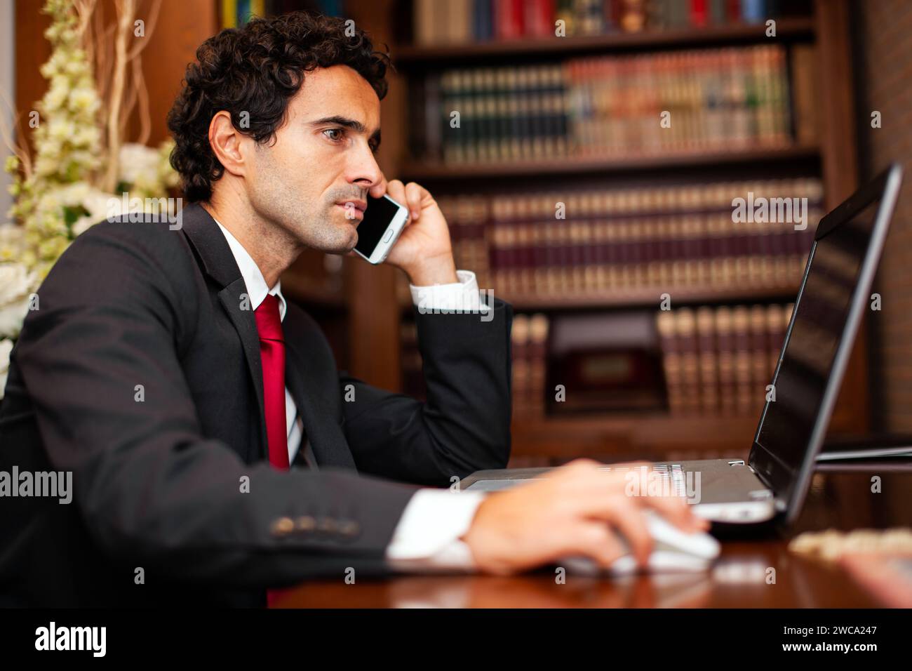 Confident male executive multitasks with a phone call and computer work ...