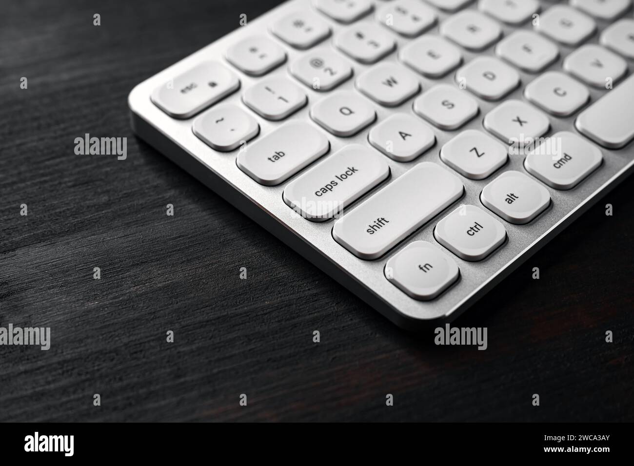 White aluminum computer keyboard on dark wooden office desk, selective ...