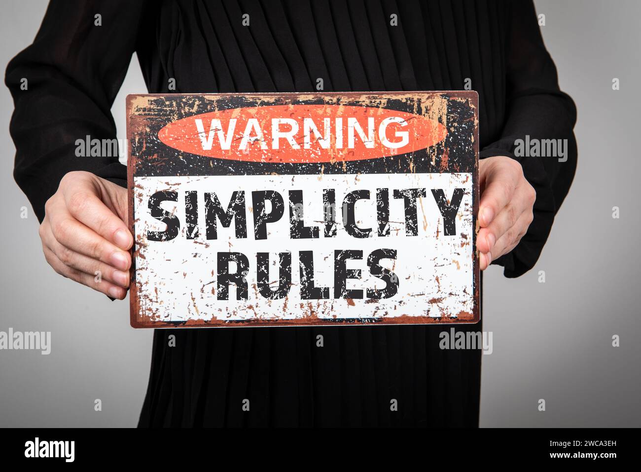 Simplicity Rules. Warning sign in woman's hands Stock Photo - Alamy