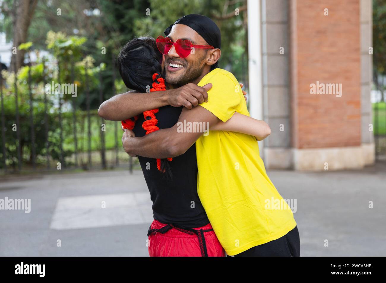 Two friends share a relaxed hug, laughing together on the street after ...