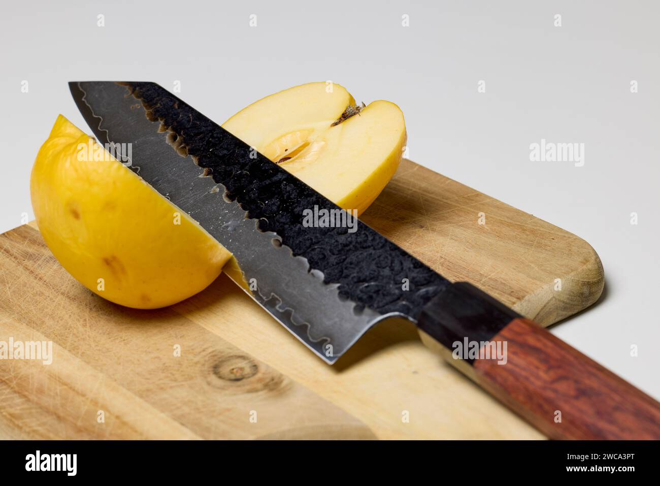 an apple cut in two by a knife on a chopper Stock Photo - Alamy