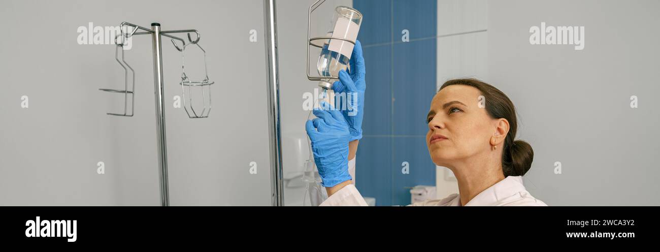 Female doctor or nurse prepares a system for transfusion of infusion ...