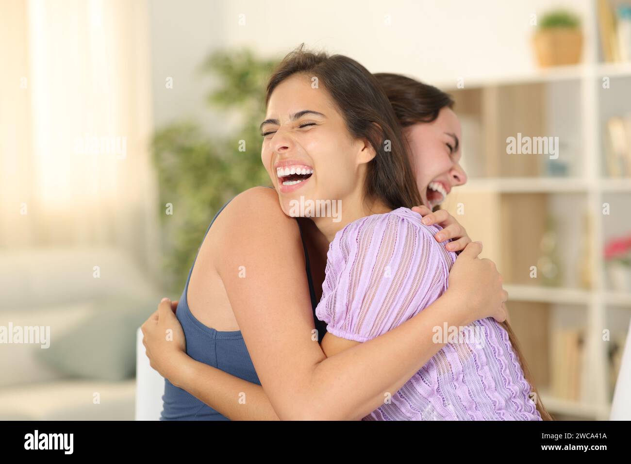 Happy friends hugging and laughing loud at home Stock Photo - Alamy
