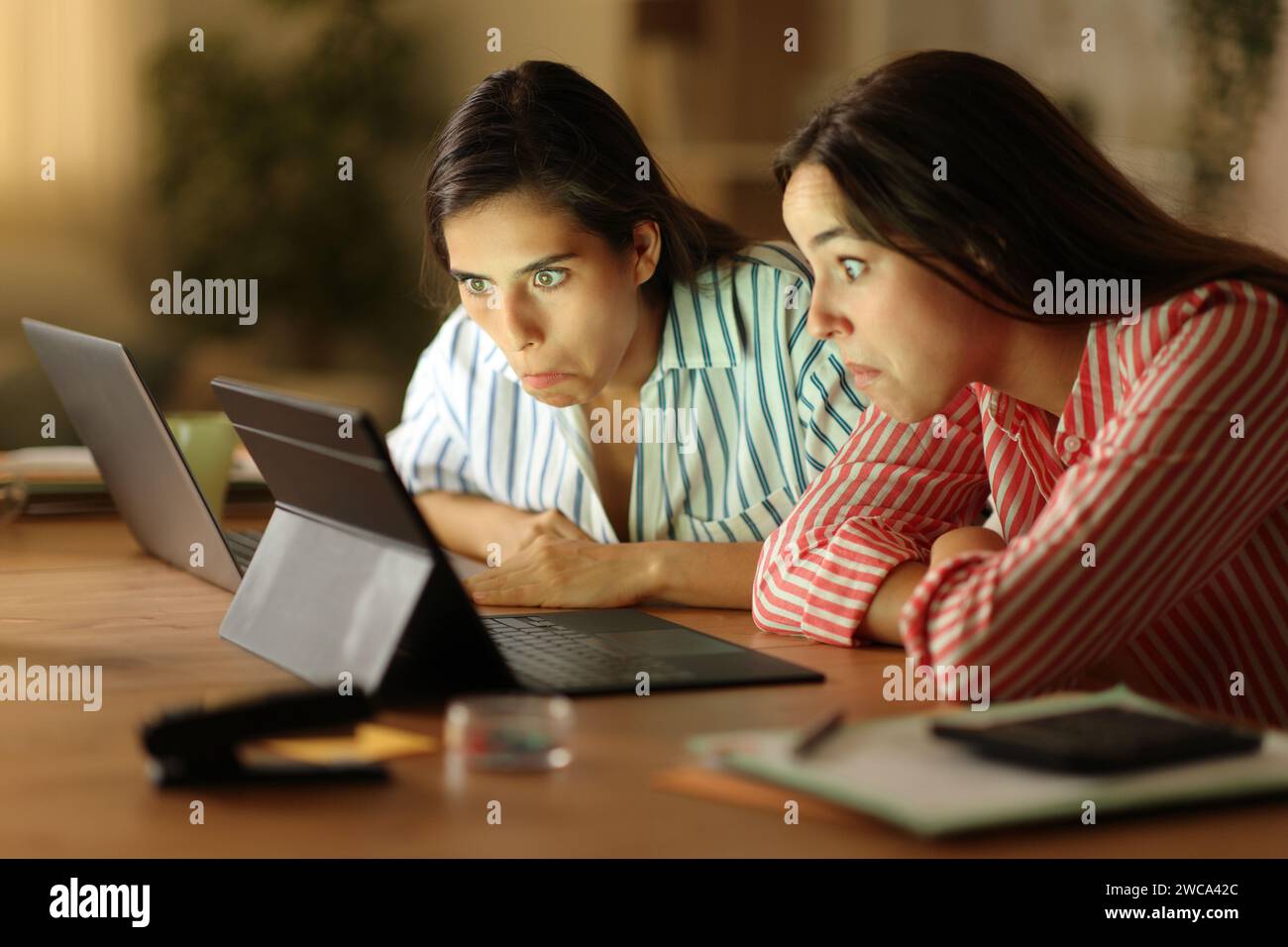 Perplexed tele workers watching media in the night at home Stock Photo ...