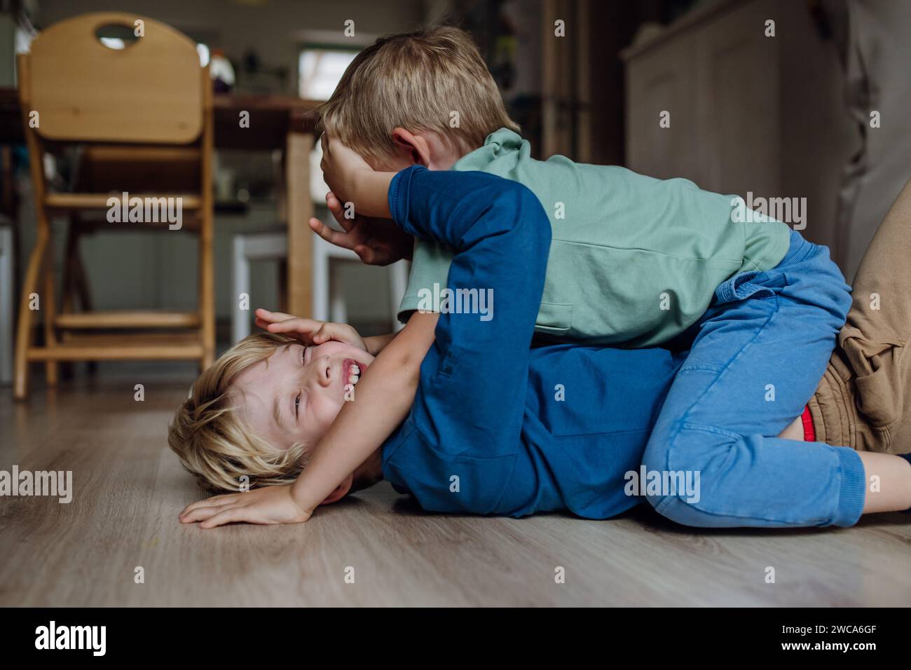 Two little boys fighting on the floor, brothers having fun at home ...