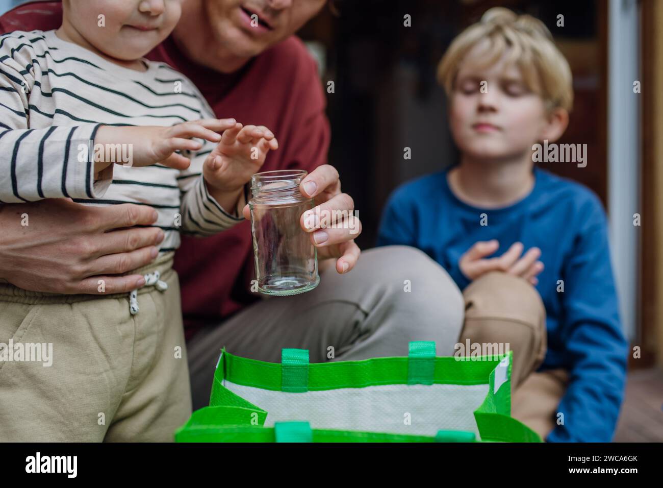 Father teaching son recycle waste. Boy sorting the waste according to ...