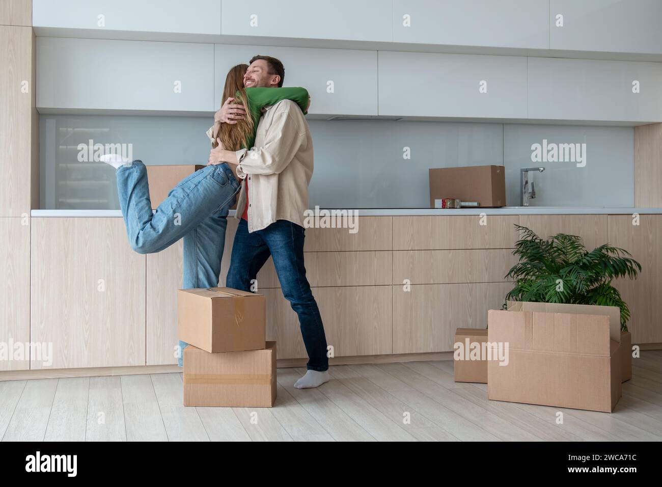 Happy overjoyed wife and husband hugging embrace on kitchen moving to ...