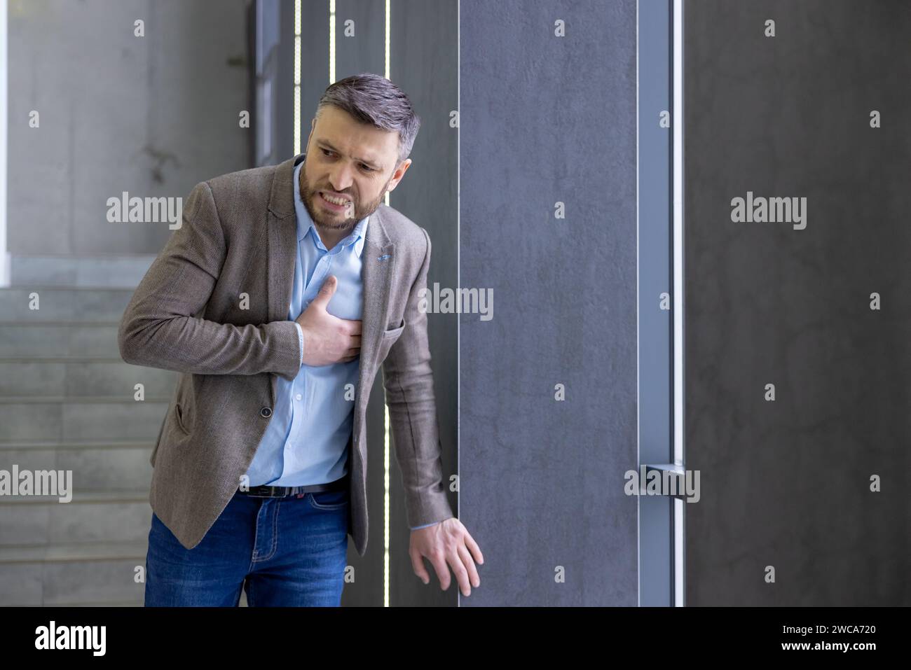 Businessman in distress clutching chest by office door, depicting heart ...