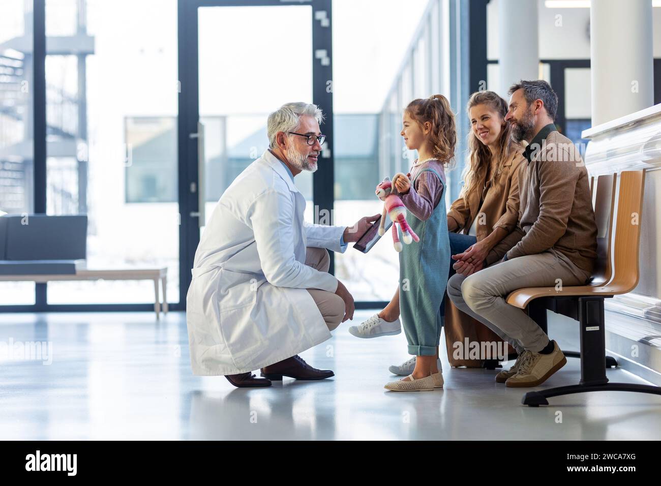 Doctor explaining results of MRI scan of brain to parents of young girl ...