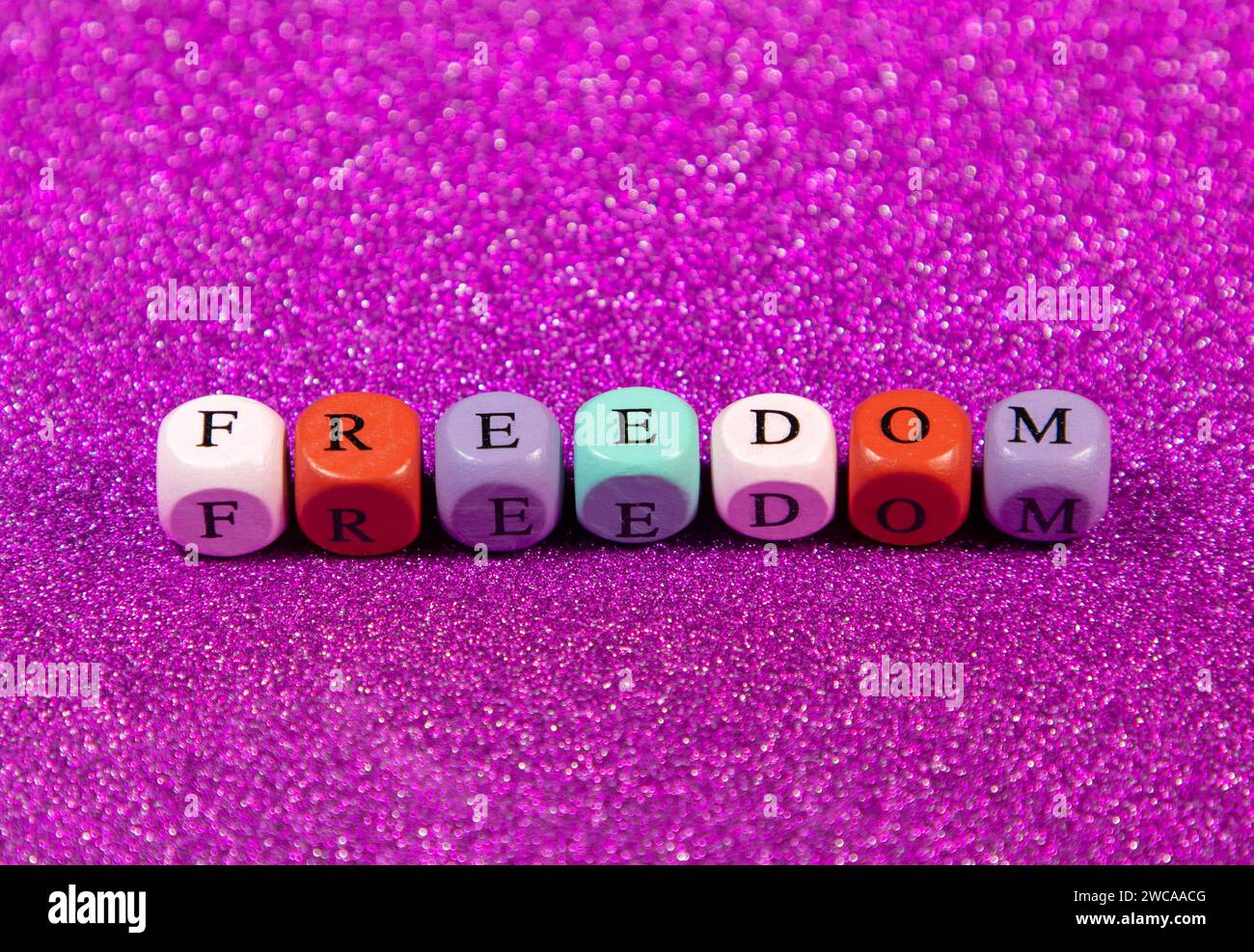 A purple background with the word 'Freedom' written with wooden cubic ...