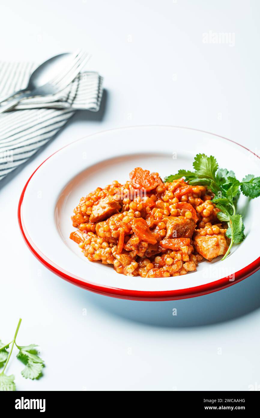 Ptitim with chicken, vegetables and cilantro, white background, copy ...