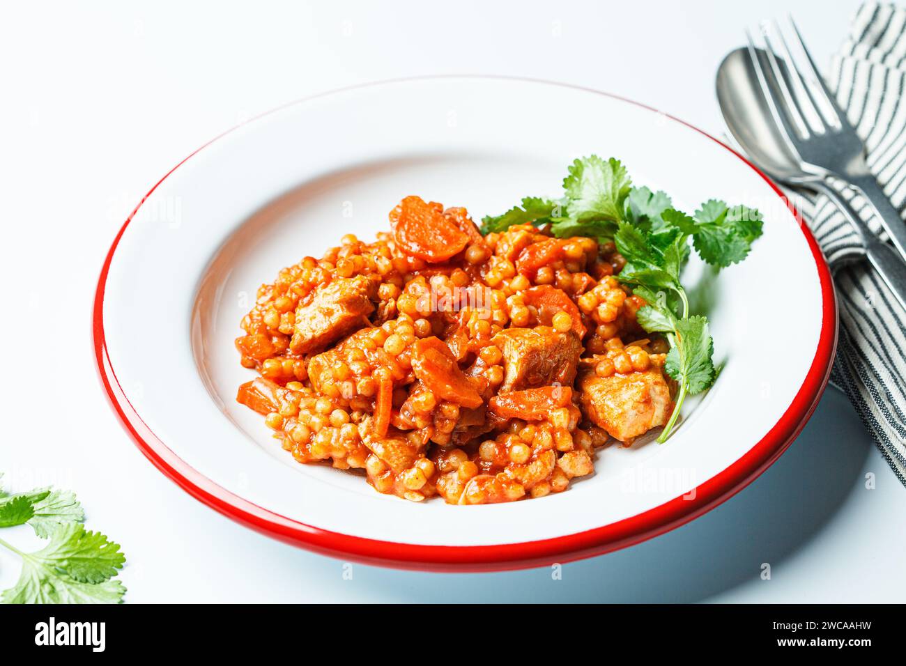 Ptitim with chicken, vegetables and cilantro, white background, close ...