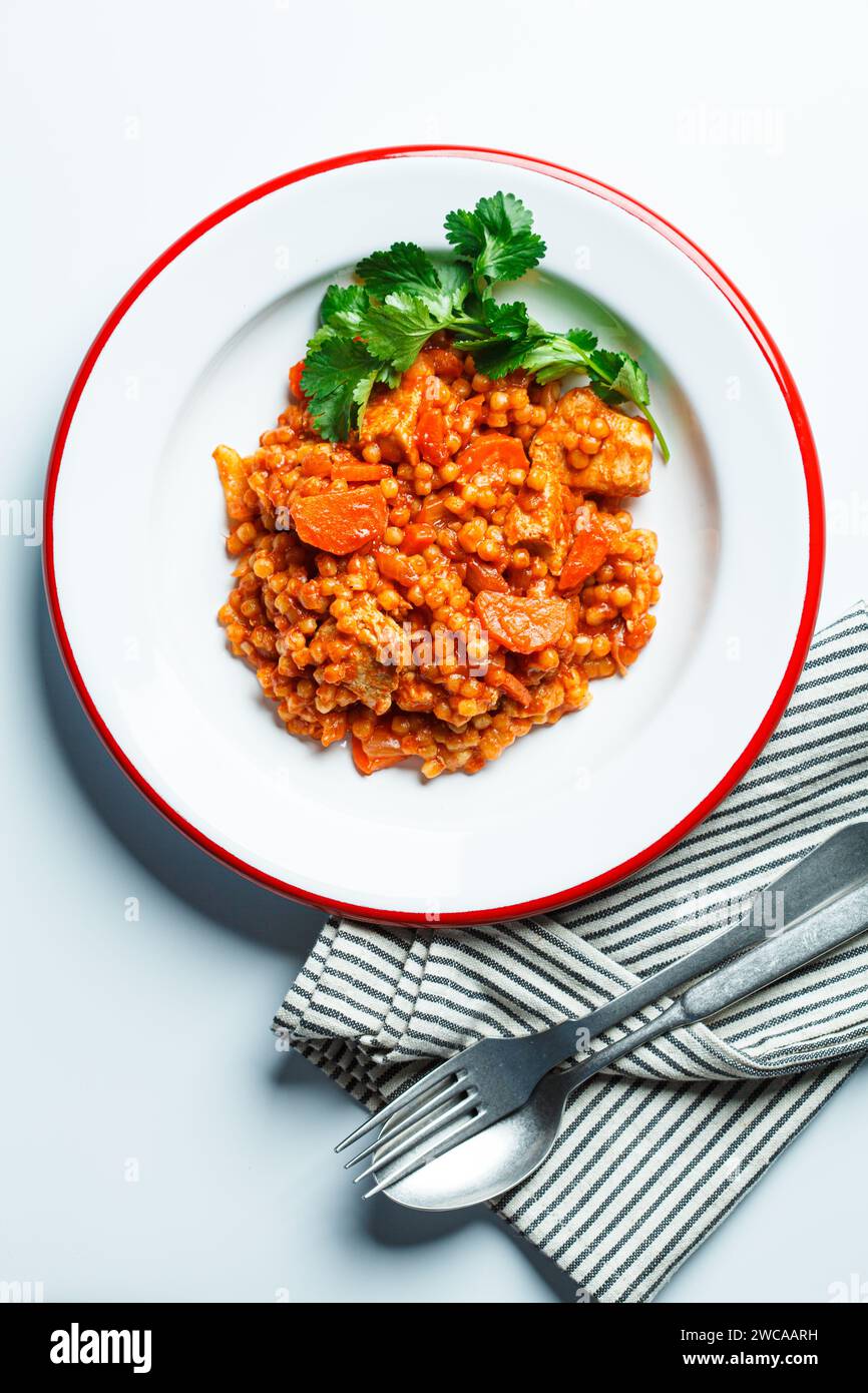 Ptitim with chicken, vegetables and cilantro, white background, top ...