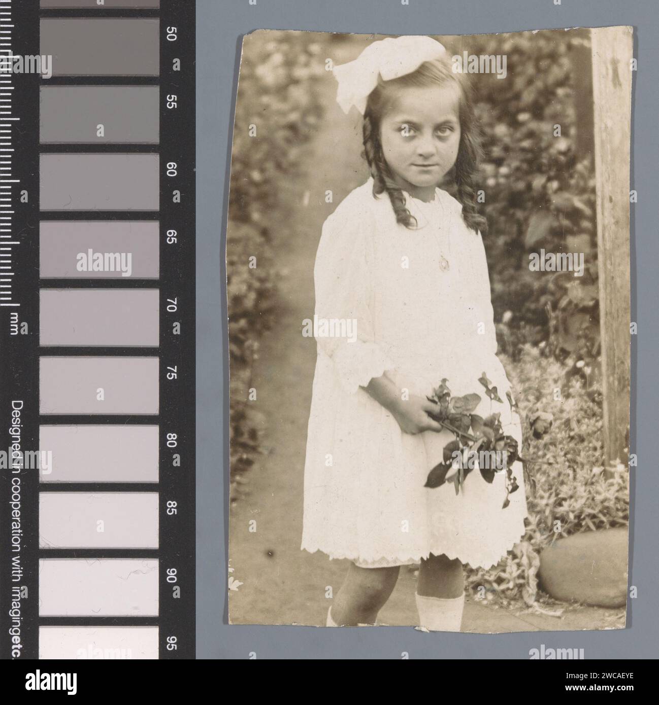 Portrait of an unknown girl in a garden with flowers in her hand ...