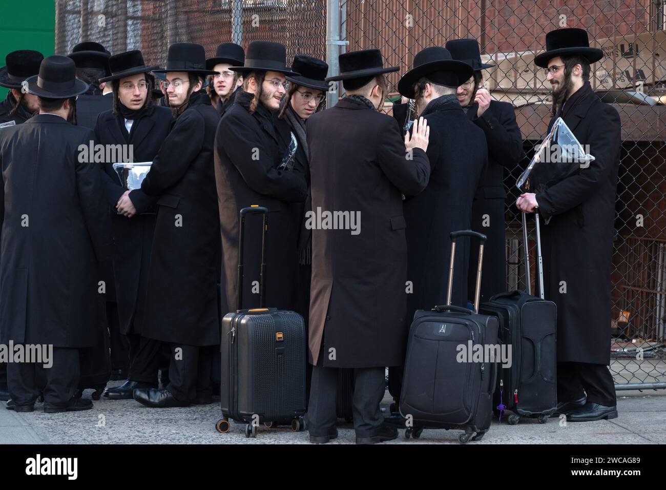 A group of orthodox Jewish students wait for a bus to transport them to ...