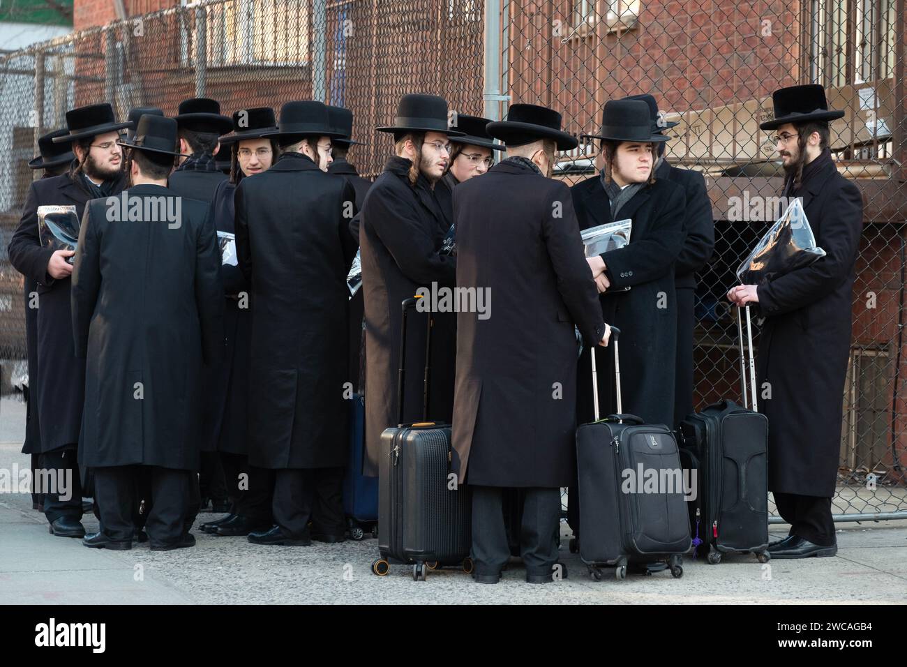 A group of orthodox Jewish students wait for a bus to transport them to ...