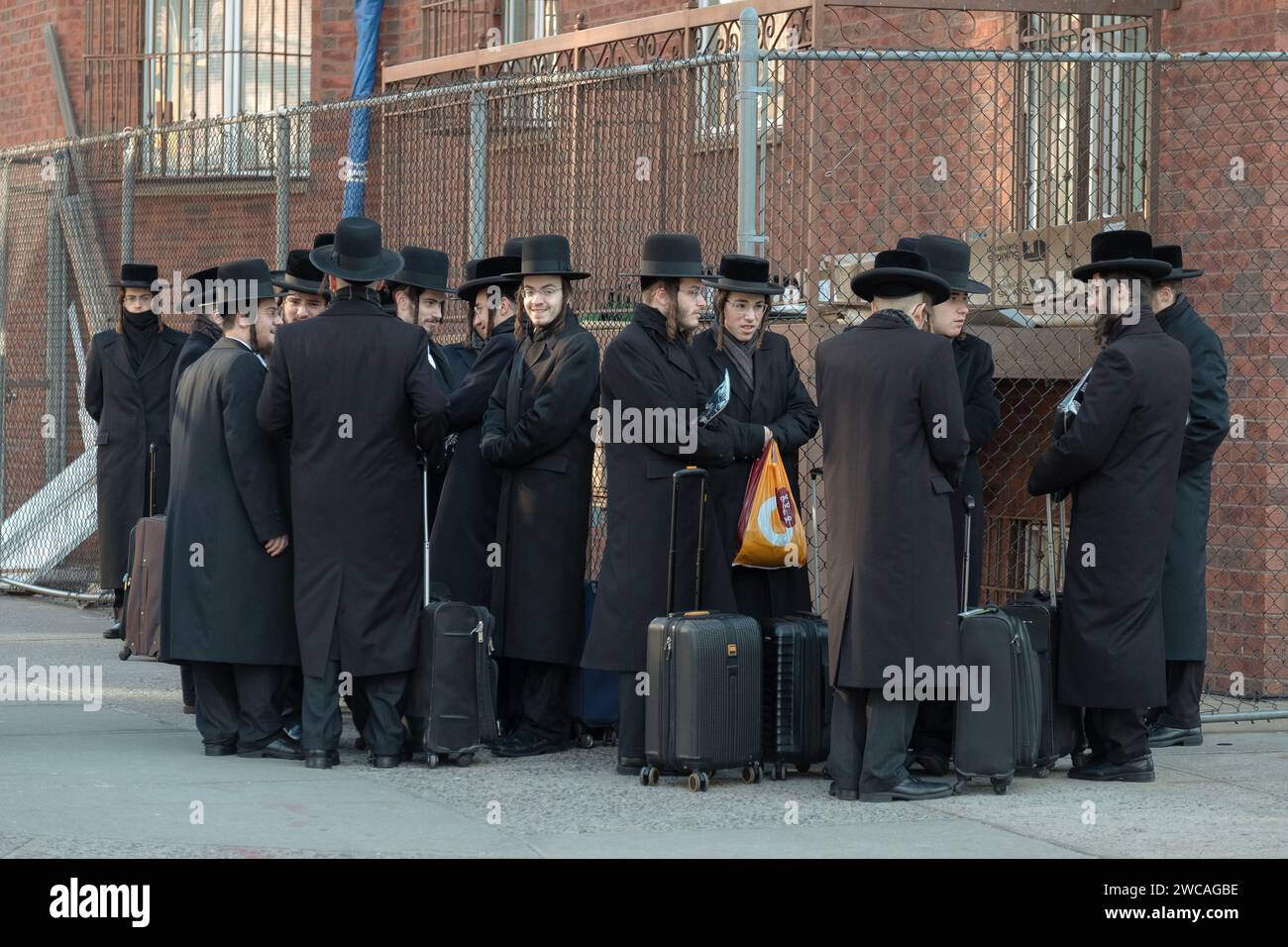 A group of orthodox Jewish students wait for a bus to transport them to ...