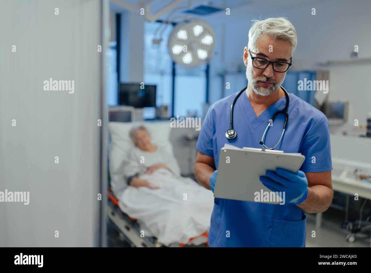 Portrait of handsome male doctor, patient in hospital bed behind. ER ...