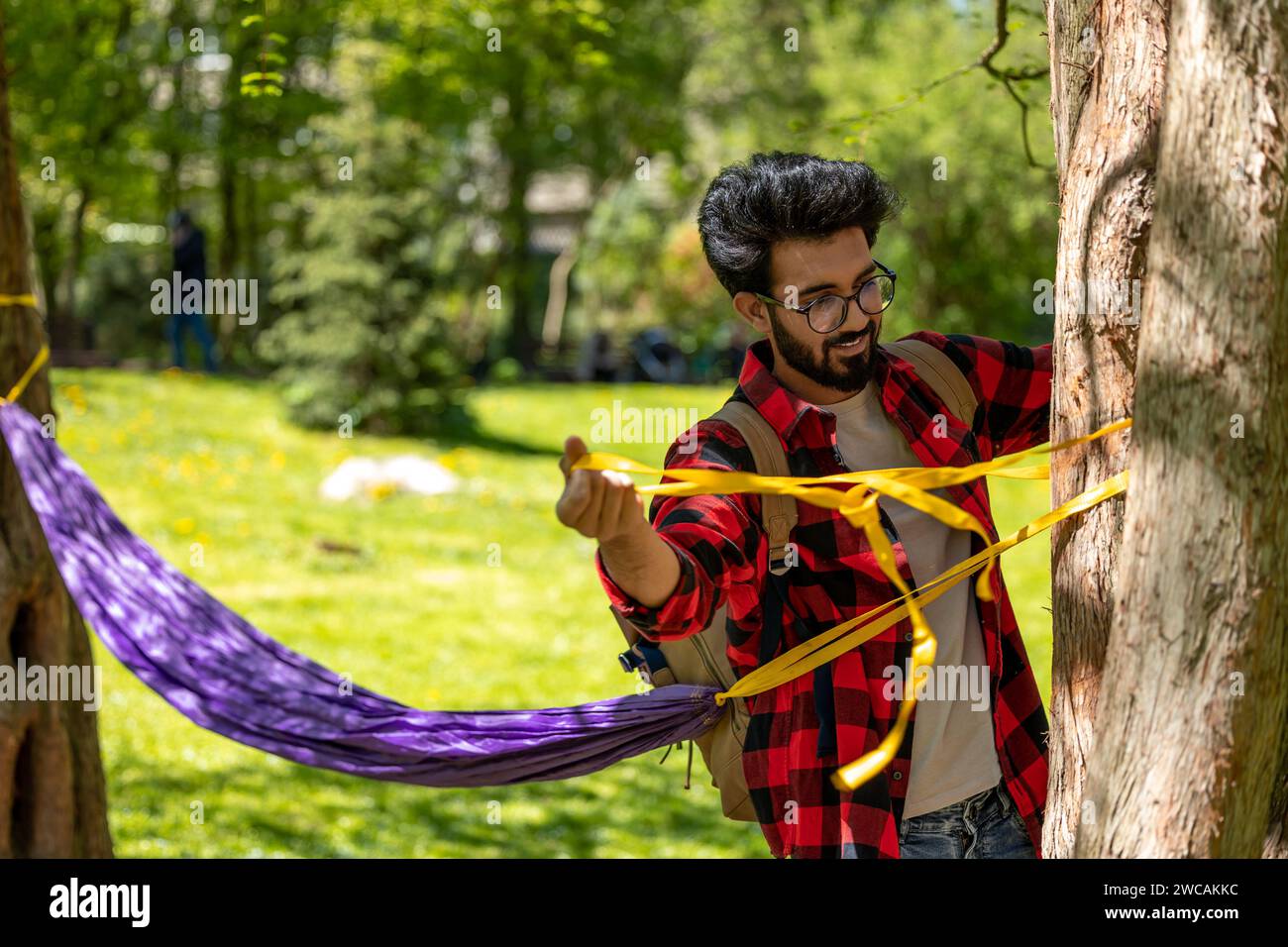 Young man fixing the ropes to the tree and fixing hammock Stock Photo ...