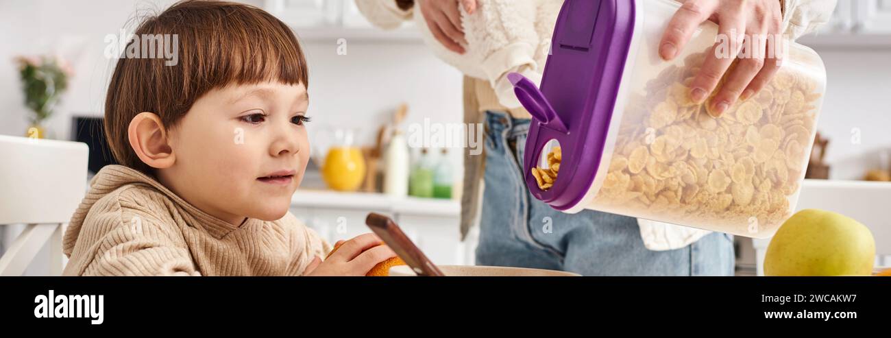 cheerful woman pouring corn flakes to her adorable toddler son while ...