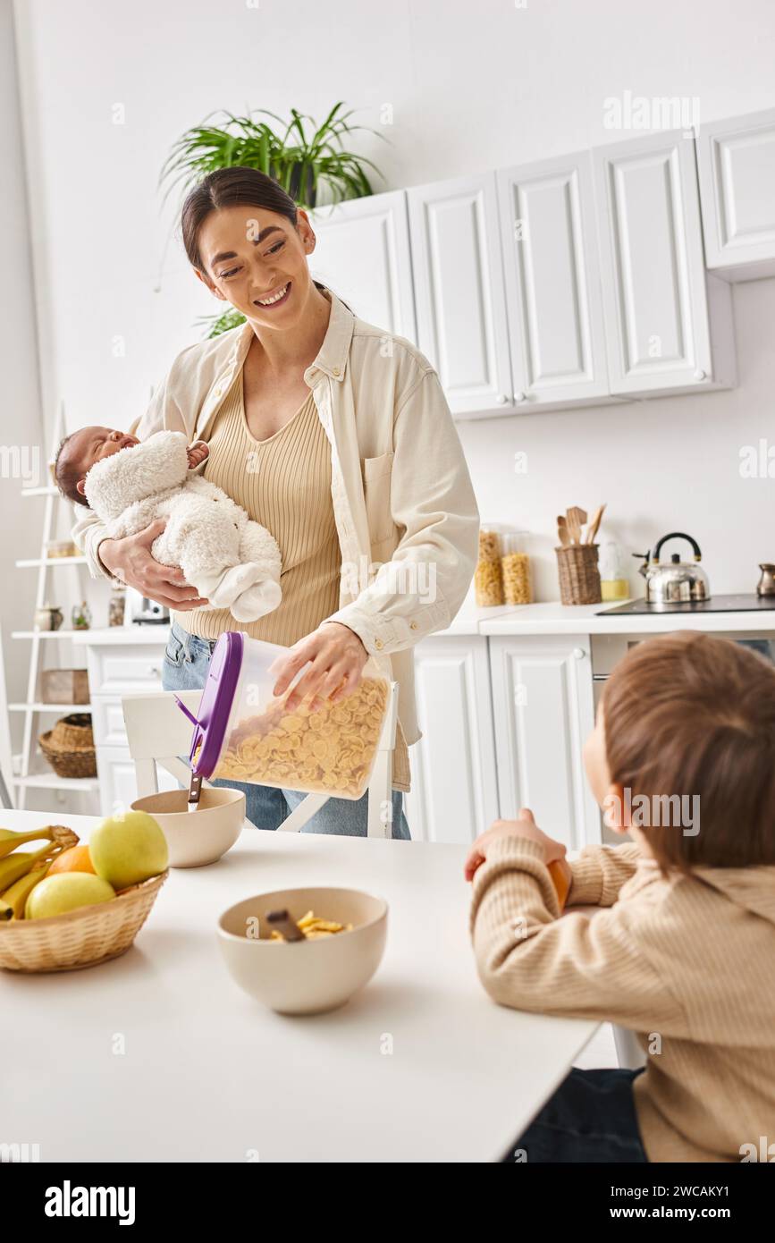 happy beautiful woman pouring corn flakes to her adorable toddler son ...