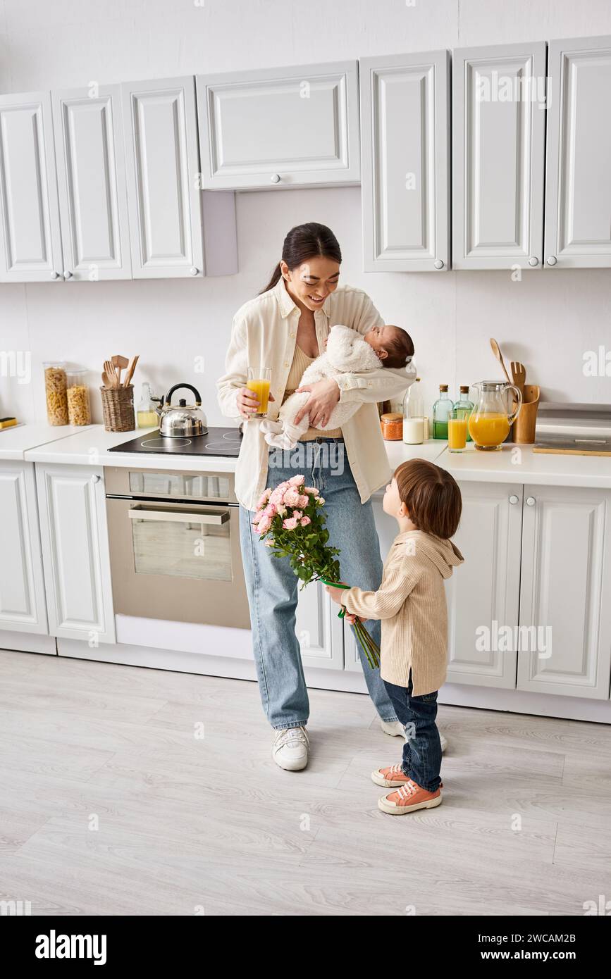 adorable toddler boy giving flowers to his attractive jolly mother with ...
