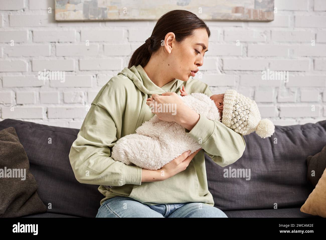 good looking loving mother in homewear comforting her cute newborn baby ...