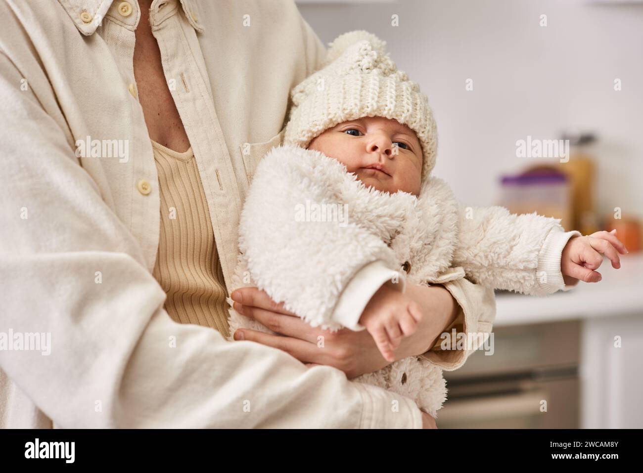 adorable newborn baby in warm comfortable outfit in hands of his caring ...