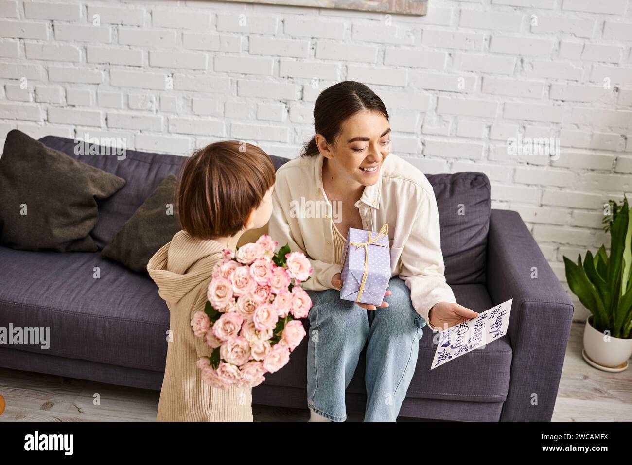cute toddler boy giving his jolly mom present and postcard with flower ...