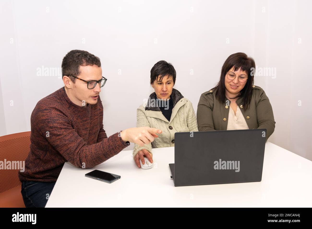 Three co-workers from an office having a conversation in a meeting room ...