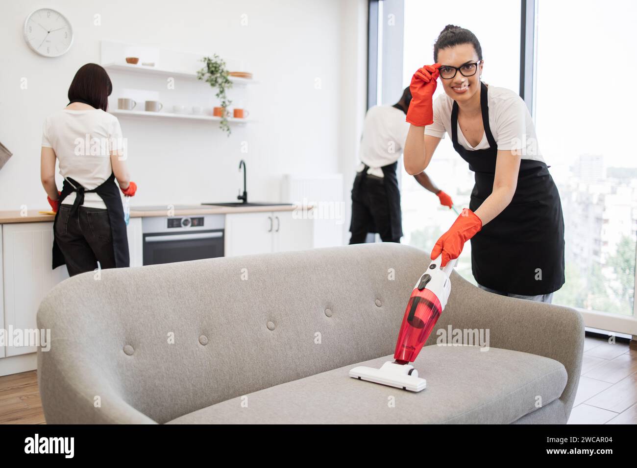 Happy smiling employees of cleaning company cleaning in bright ...