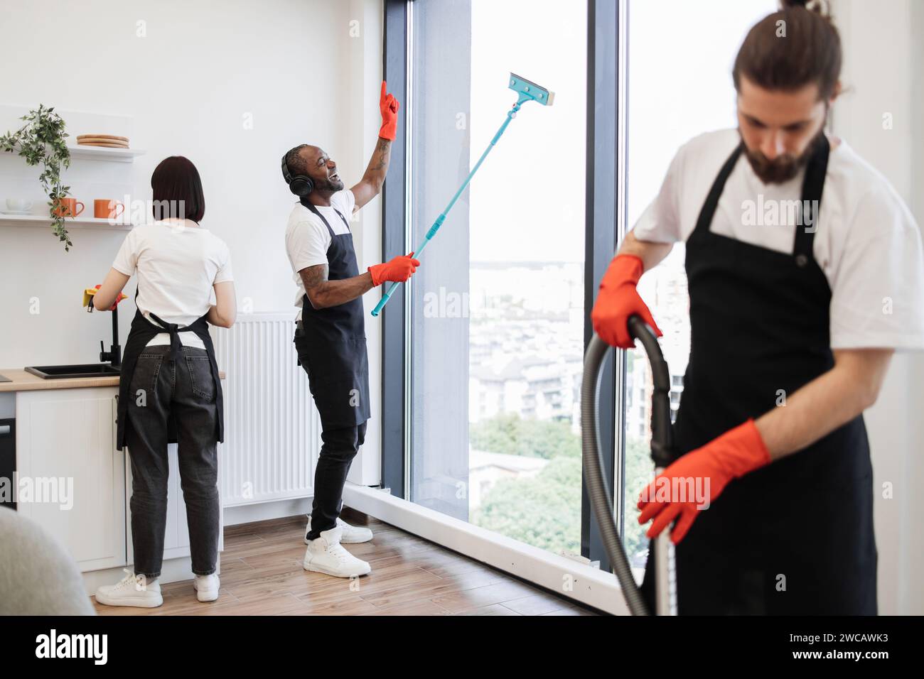 African cleaning company worker in headphones washing panoramic windows ...