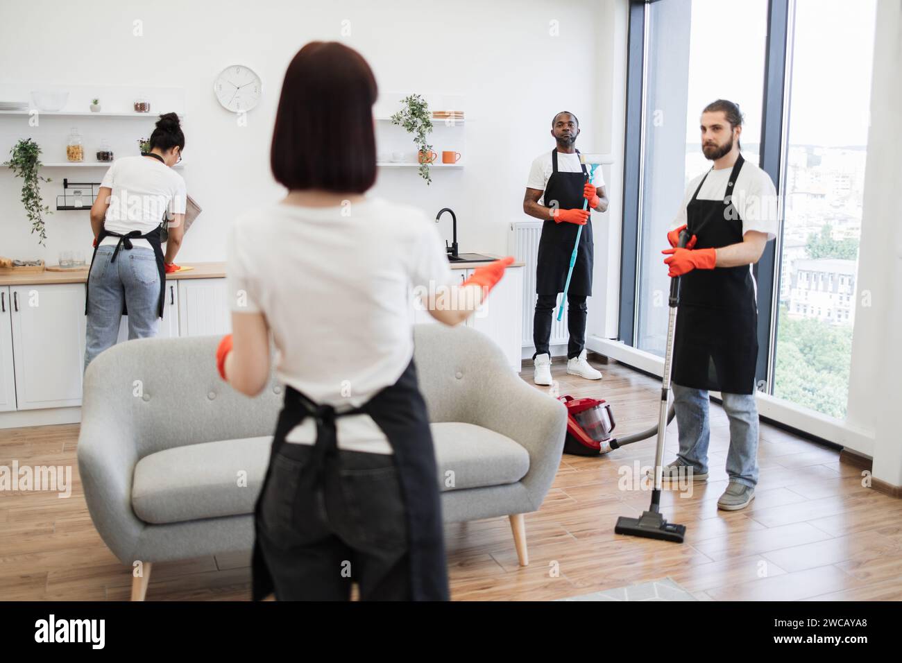 Group of janitors in uniform cleaning office with cleaning equipment ...