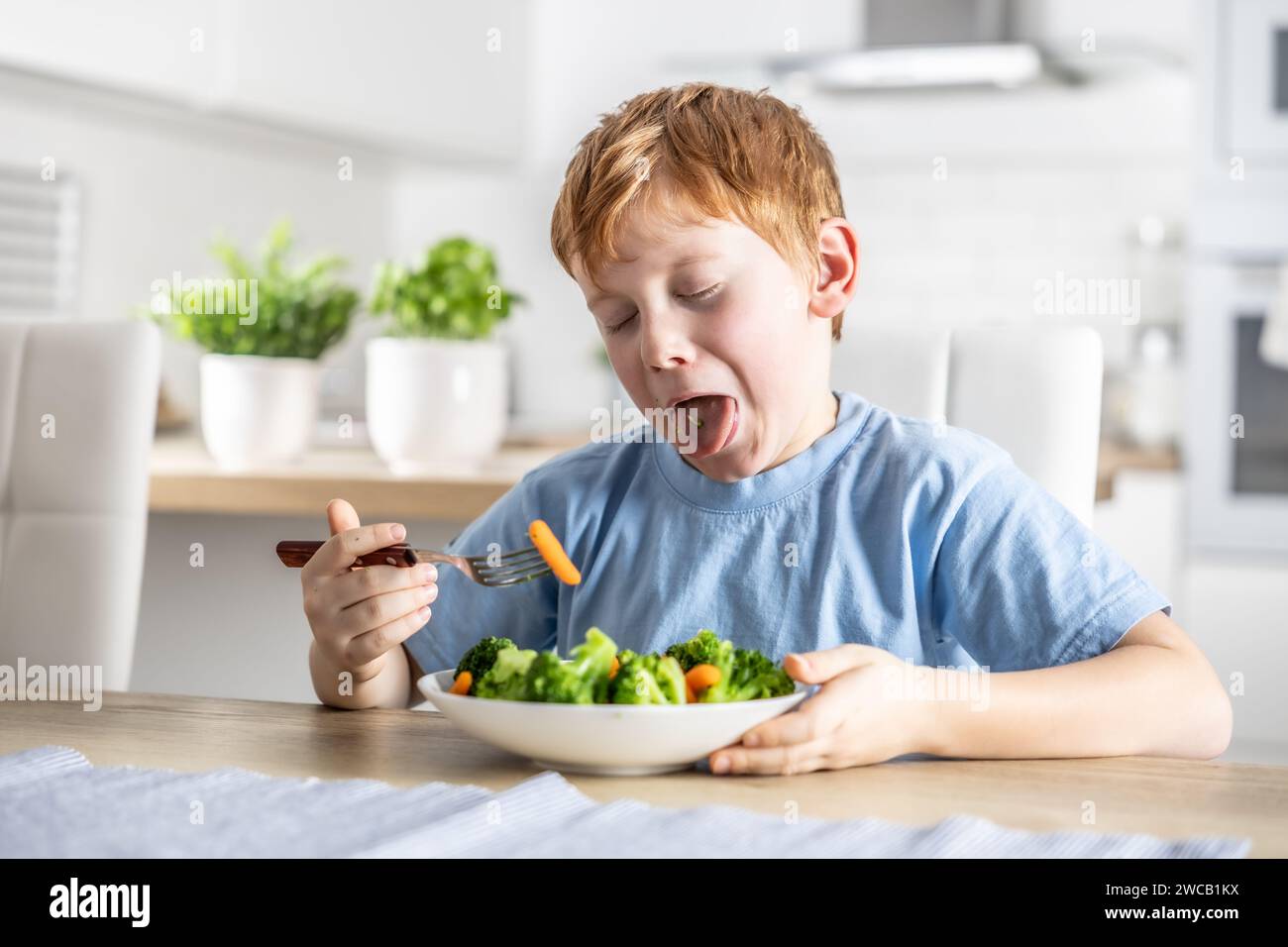 The little boy looks with distaste at the carrot on his fork Stock ...