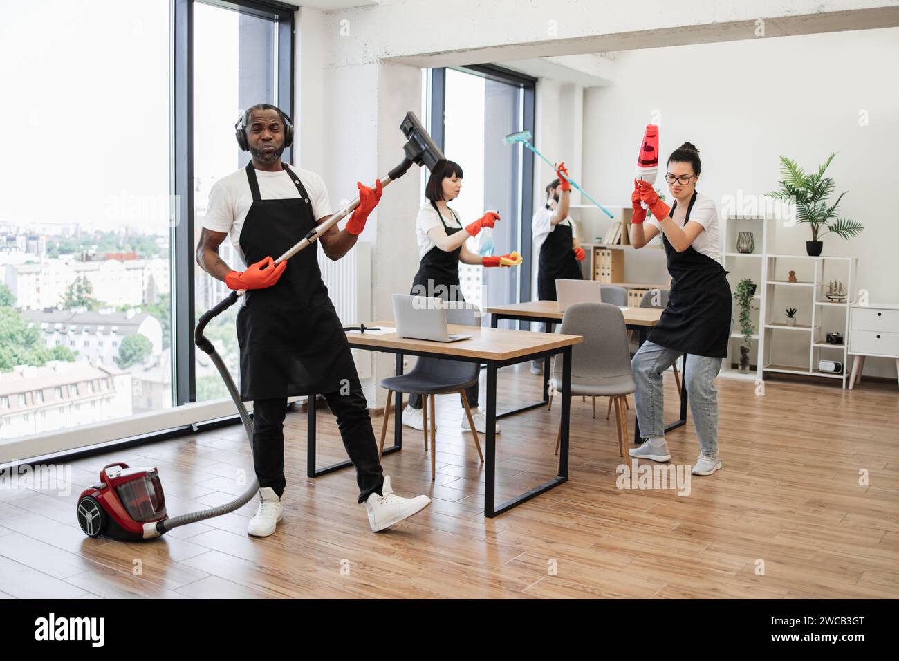 African man with modern vacuum cleaner and three cleaners dancing Stock ...