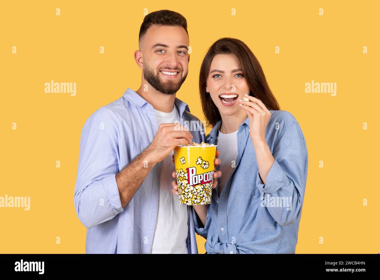 Couple sharing popcorn and smiles, enjoying movie night together Stock ...