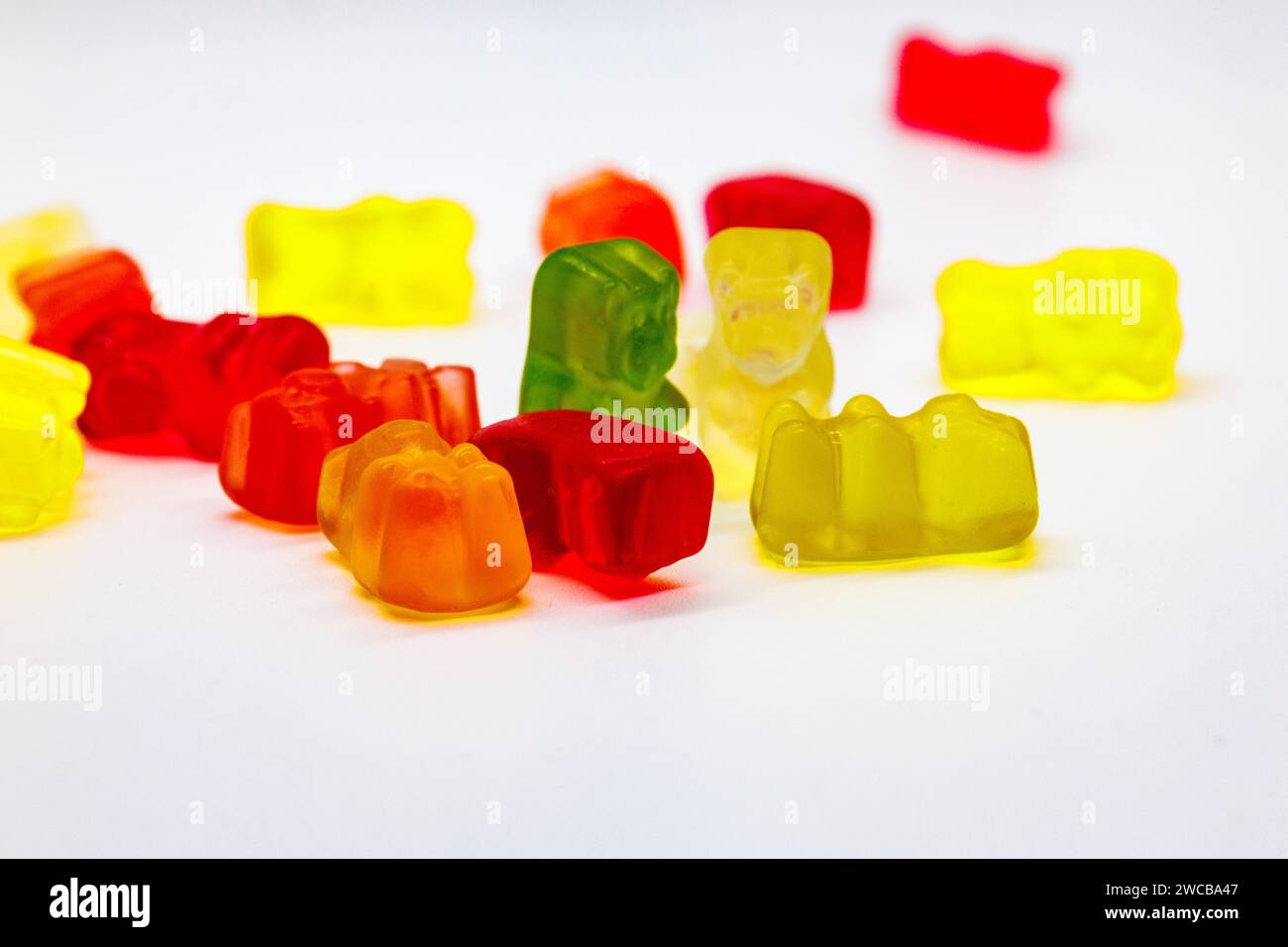 The multi-colored gummy bears arranged on a pristine white surface ...