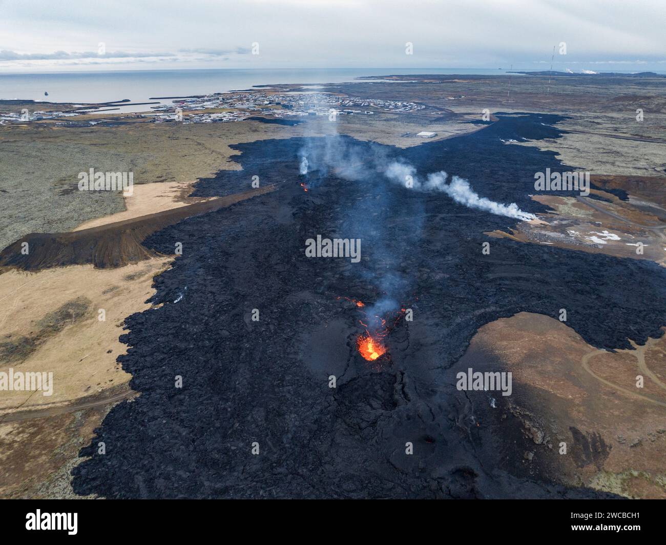 An areal view of the lava field with the main active vent, the town of ...