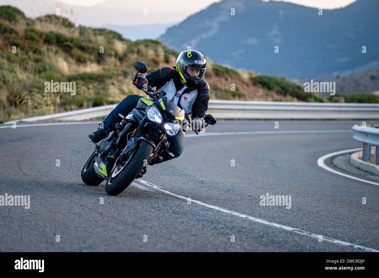 young man driving his motorcycle on a bend on the road, photography on ...