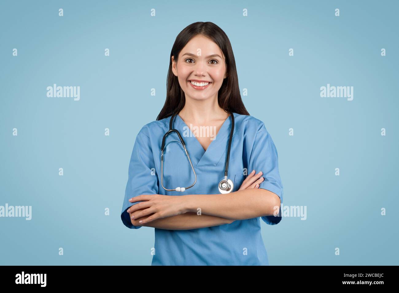 Smiling nurse with arms crossed, blue background Stock Photo - Alamy