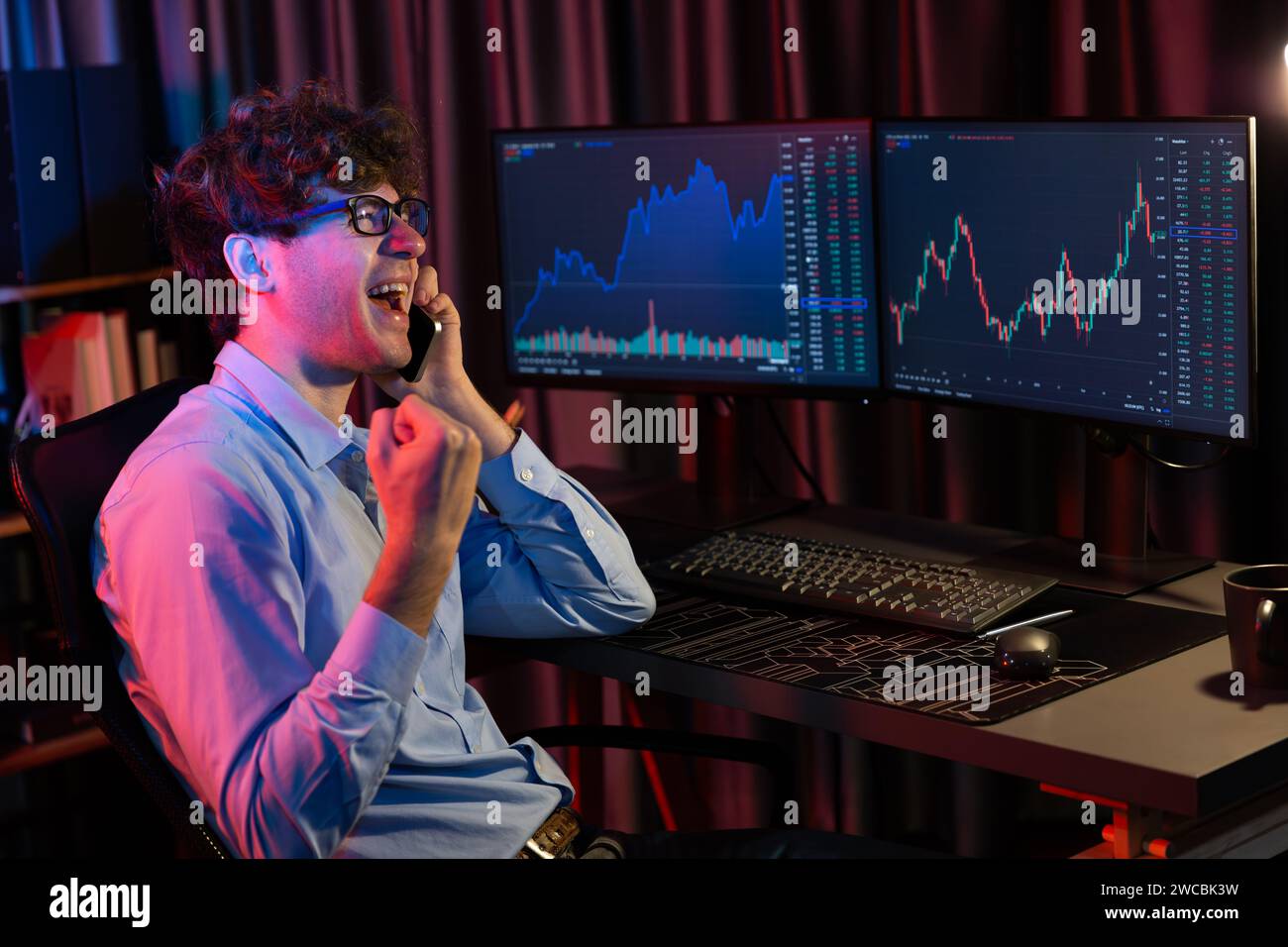 Successful business trader calling on smartphone with raising fist up ...