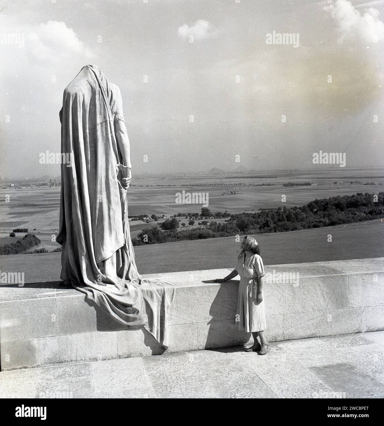 1950s, historical, a lady standing at a limestone wall, looking up at a ...