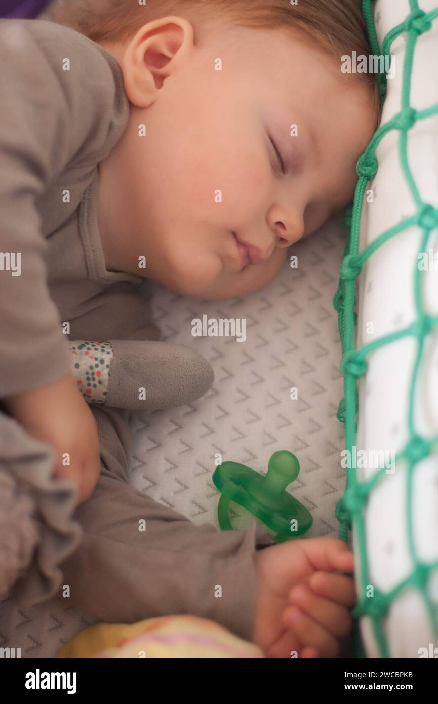 Beautiful little baby boy sleeping peacefully lying on side in bed ...