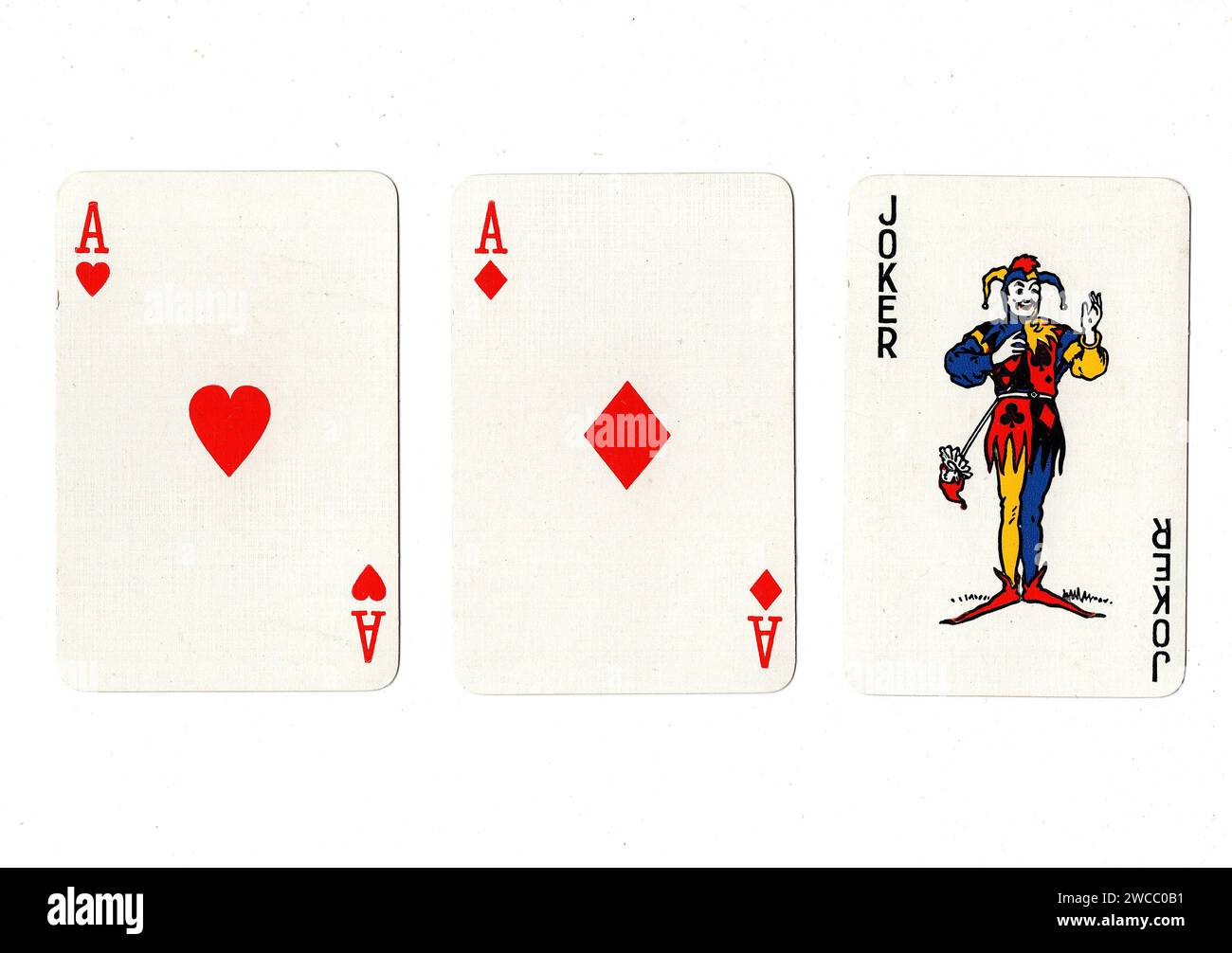 Vintage playing cards showing a pair of red aces and a joker isolated ...
