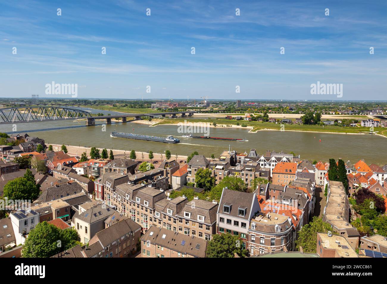 View at the Waal river with cargo riverboats passing the Dutch city of ...