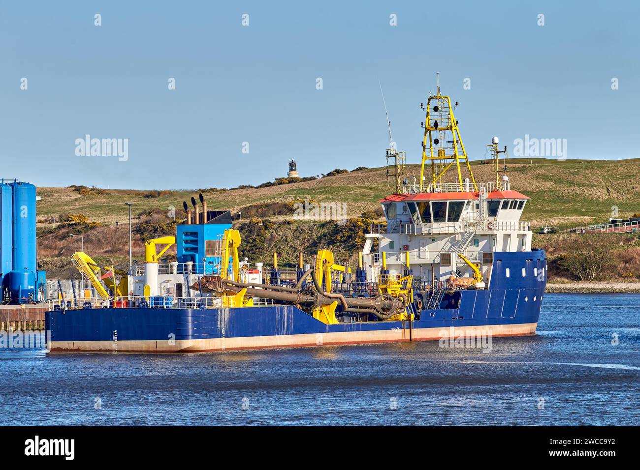 Dredger vessel in marine port during sunny day with mountain on the ...