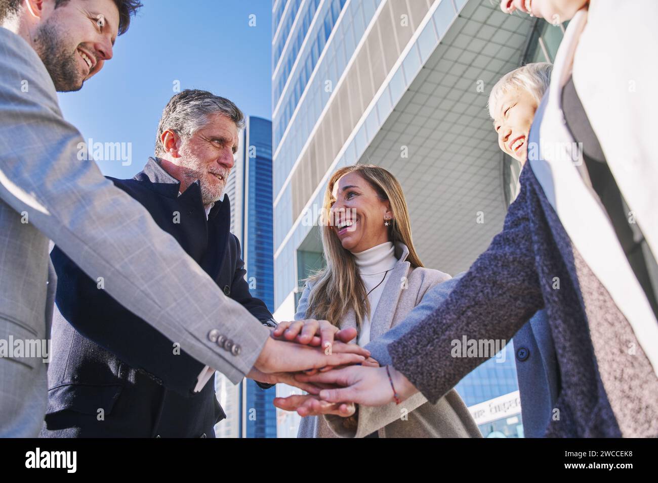 Group of positive professional coworker people stacking hands outdoors ...